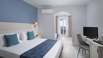 Quarto de hotel com cama, escrivaninha, televisão e vista para o exterior.