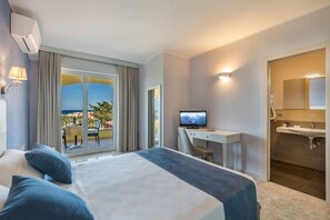 Quarto de hotel com cama, escrivaninha, televisão e banheiro.