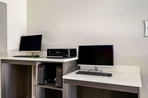 Um espaço de trabalho com computador de mesa, monitor, teclado e impressora.