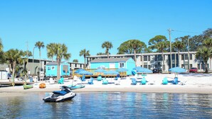 Um hotel na praia com cadeiras, guarda-sóis e um jet ski.