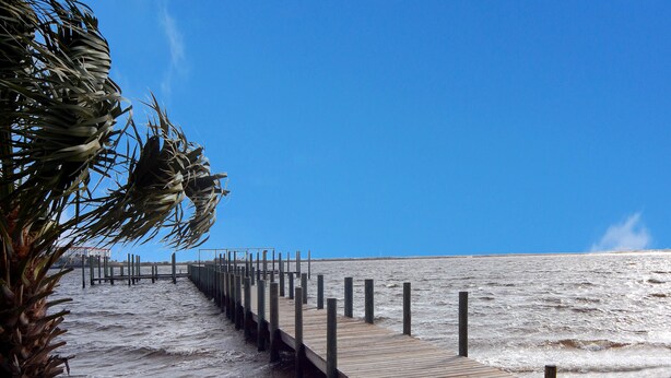 Um cais de madeira que se estende sobre a água, com um céu claro.