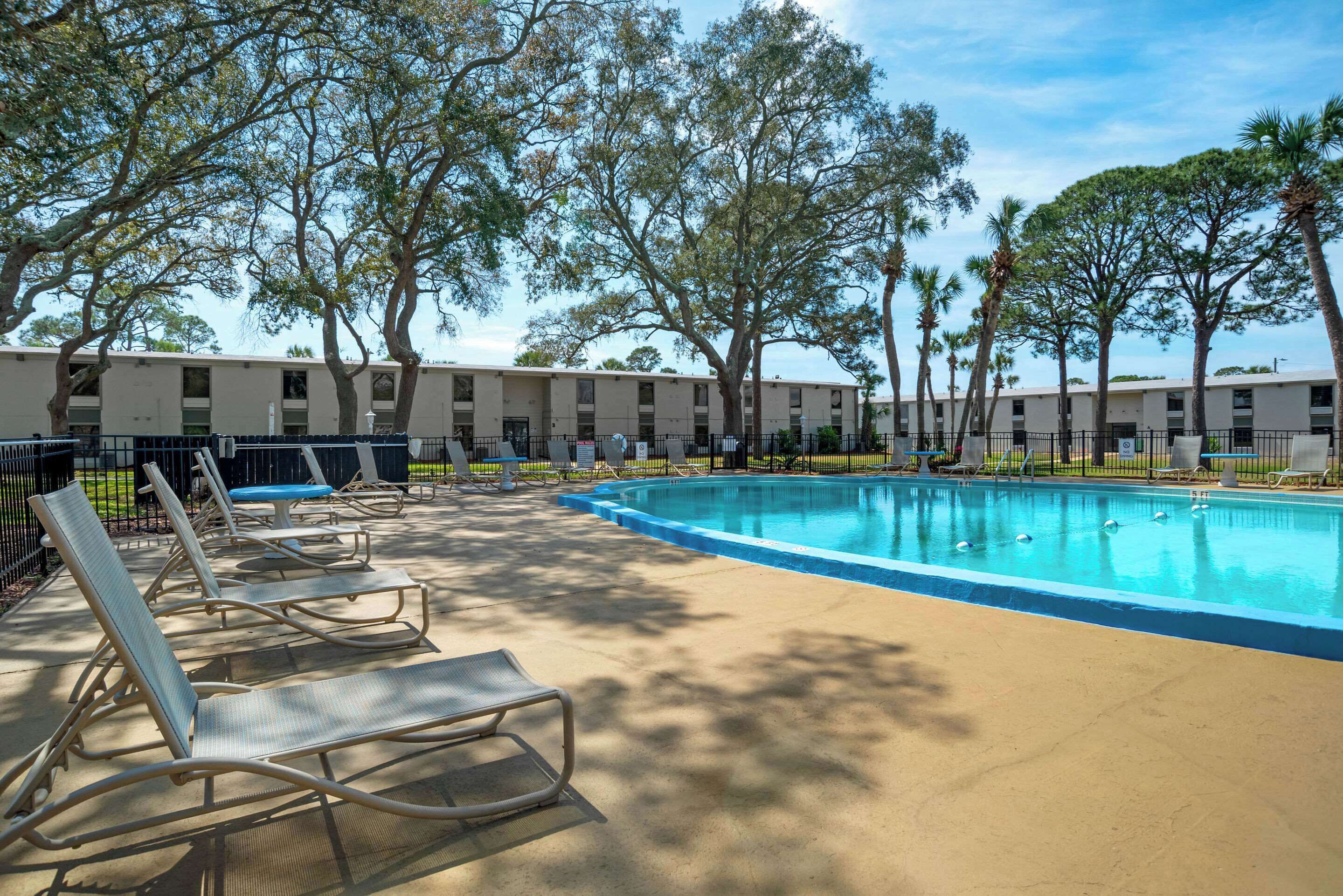Uma área de piscina com espreguiçadeiras e um edifício ao fundo.