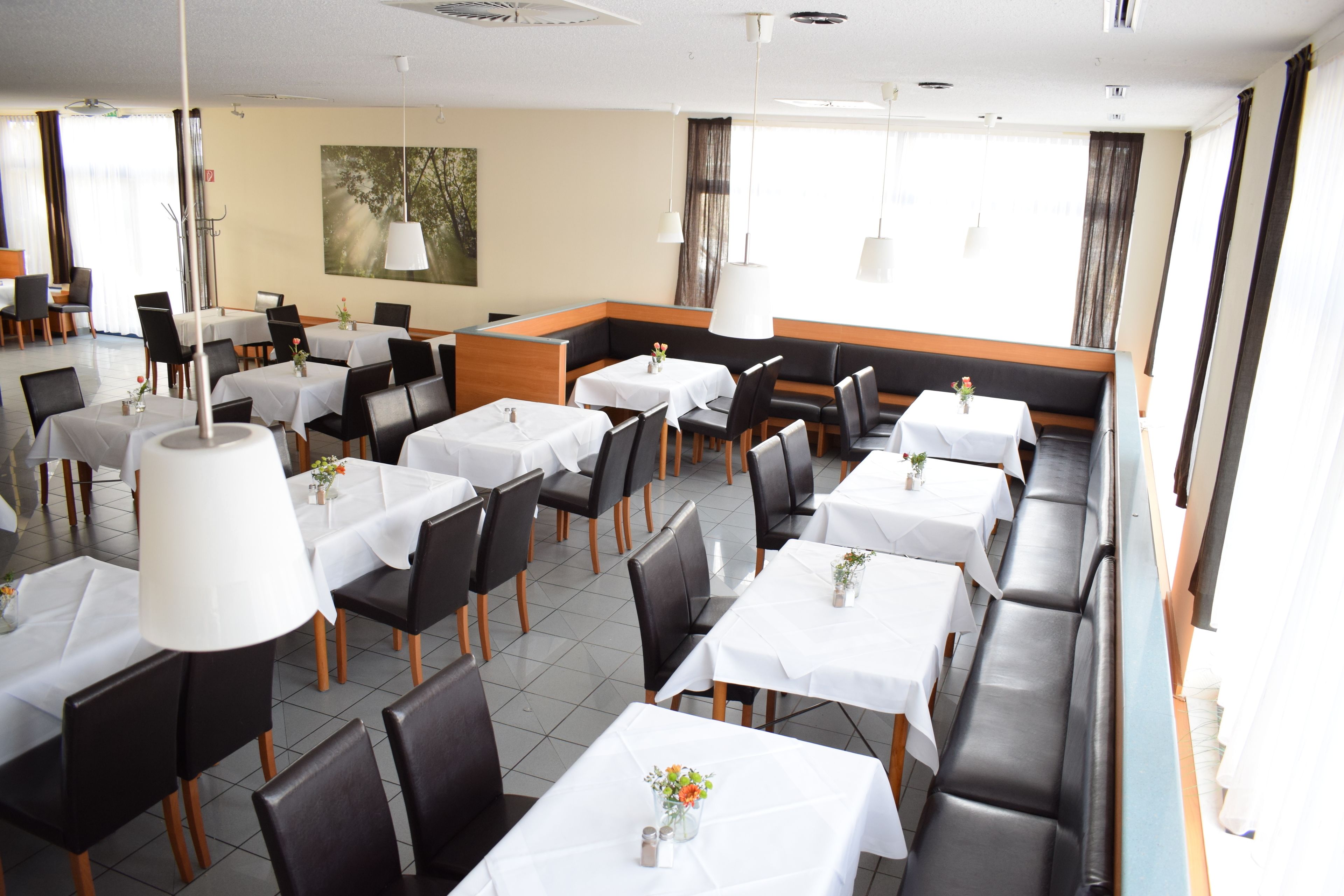 Uma sala de jantar de hotel com várias mesas e cabines, dispostas numa configuração ampla.