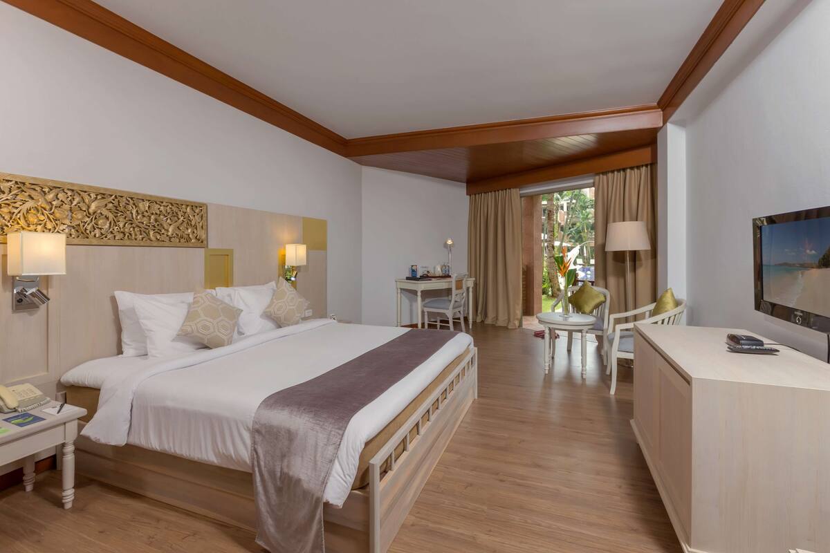 Quarto de hotel com cama, escrivaninha e televisão.