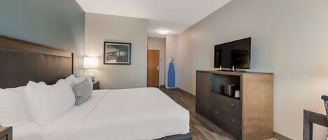 Quarto de hotel com uma cama grande, televisão na parede, penteadeira e escrivaninha.
