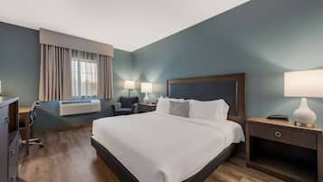 Quarto de hotel com uma cama grande, mesas de cabeceira, uma escrivaninha e uma cadeira.