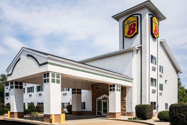 Um hotel Super 8 com área de estacionamento coberta, fachada de pedra e um letreiro 'Super 8' bem visível no edifício.