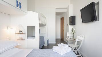 Quarto de hotel moderno com cama, escrivaninha, televisão e um pequeno espaço para sentar.