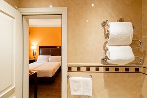 Quarto de hotel com cama, mesa de cabeceira e banheiro com porta-toalhas.