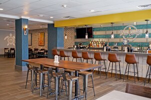 Um restaurante com área de bar, mesas de madeira e banquetas.