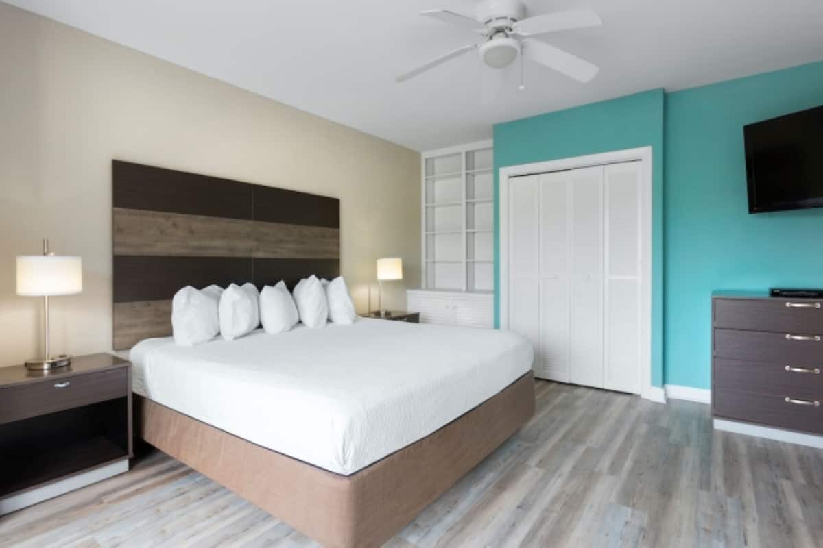 Quarto de hotel moderno com uma cama grande, um ventilador de teto, televisão e um guarda-roupa.