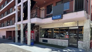 Um hotel Travelodge com publicidade da Coca-Cola, uma placa de saída visível e um estacionamento cheio de carros.