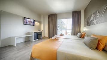 Quarto de hotel com cama, secretária, televisão e vista para o exterior.