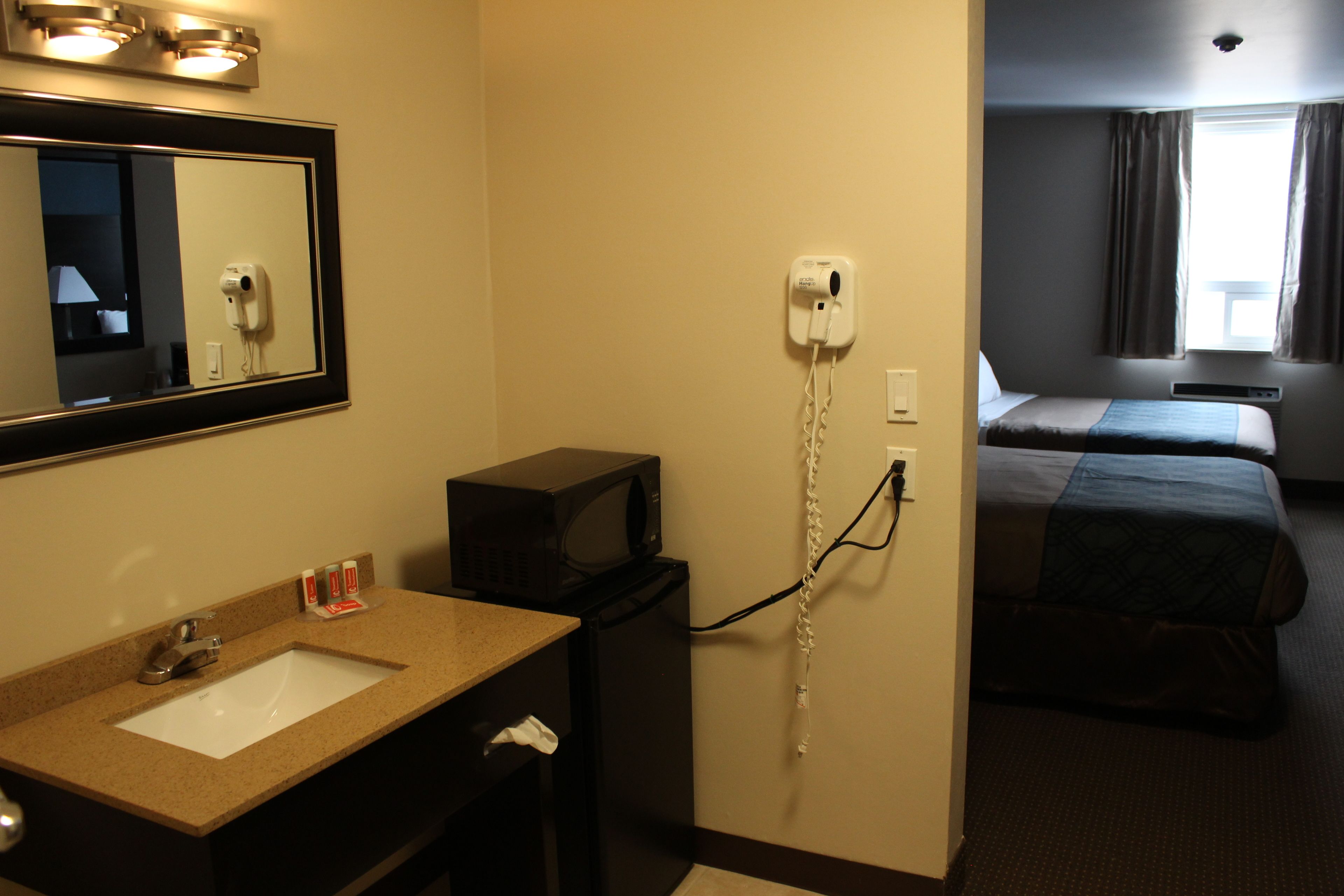 Quarto de hotel com banheiro, uma cama e micro-ondas.