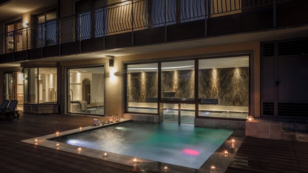 Um hotel moderno com piscina, área de estar externa e varanda com guarda-corpo.