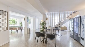 Amplo espaço interno com mesa de bilhar, área de estar e máquina de vendas.