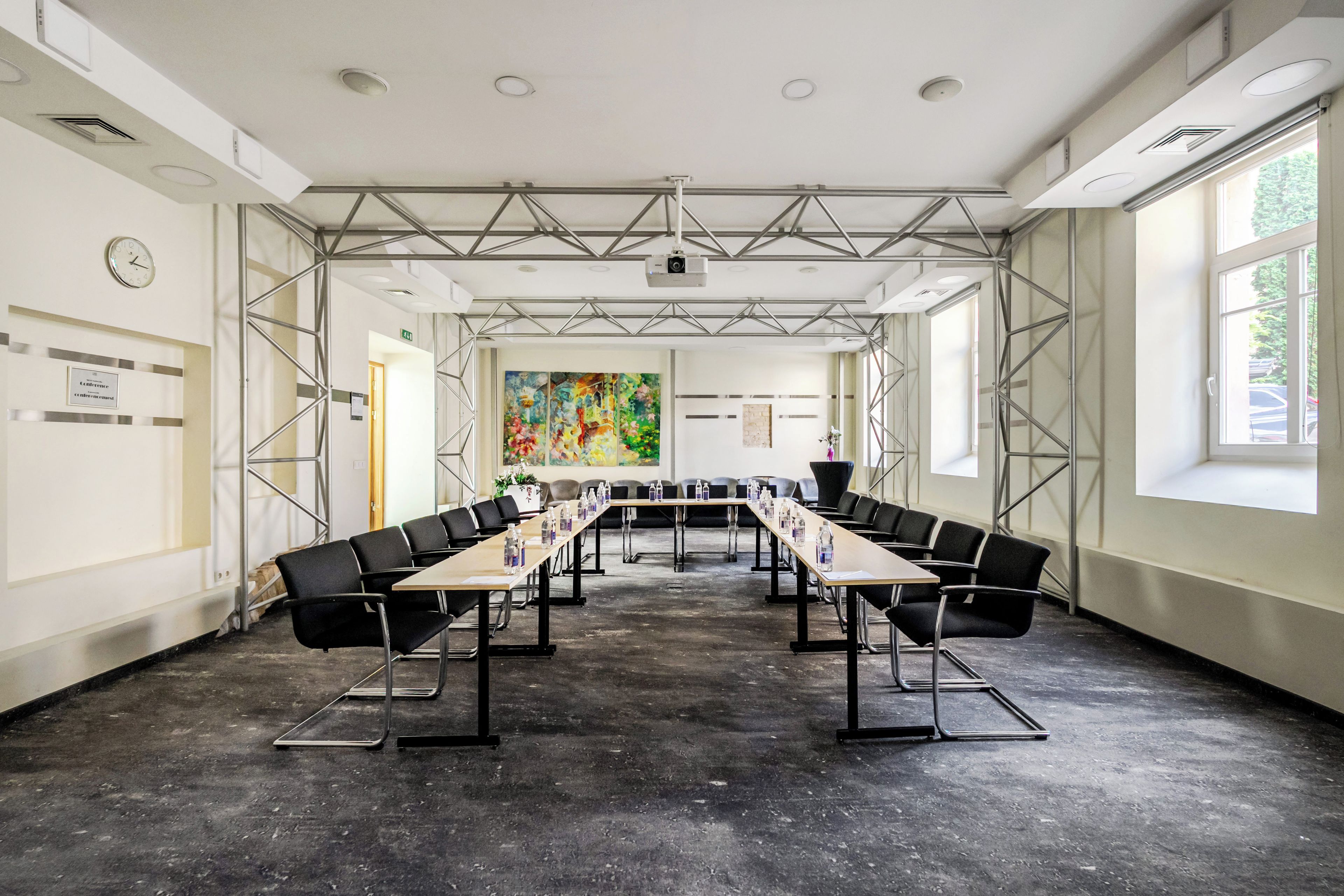 Uma sala de conferências com uma mesa comprida, cadeiras e uma tela de projeção.