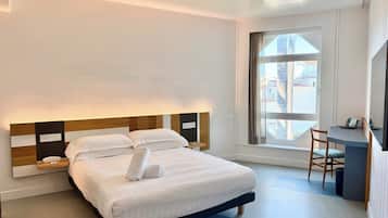 Quarto de hotel moderno com uma cama grande, mesas de cabeceira, uma escrivaninha e uma janela com vista.
