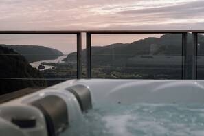Uma banheira de hidromassagem com vista para um rio e colinas.