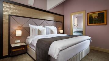 Quarto de hotel com uma cama grande, mesas de cabeceira, um espelho e um quadro na parede.