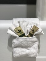 Toalha branca com duas garrafas de shampoo e sabonete em um banheiro.