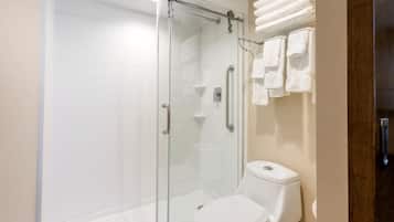 Um banheiro moderno com chuveiro em gabinete de vidro, vaso sanitário branco e porta-toalhas com toalhas dobradas.