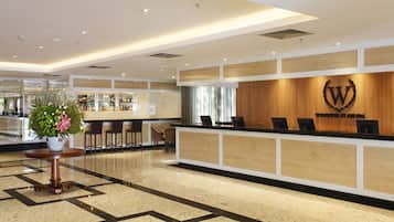 Uma área de recepção de hotel com balcão, bar e espaço para sentar.