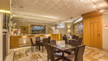 Um saguão de hotel com área de bar, mesas e cadeiras de jantar.