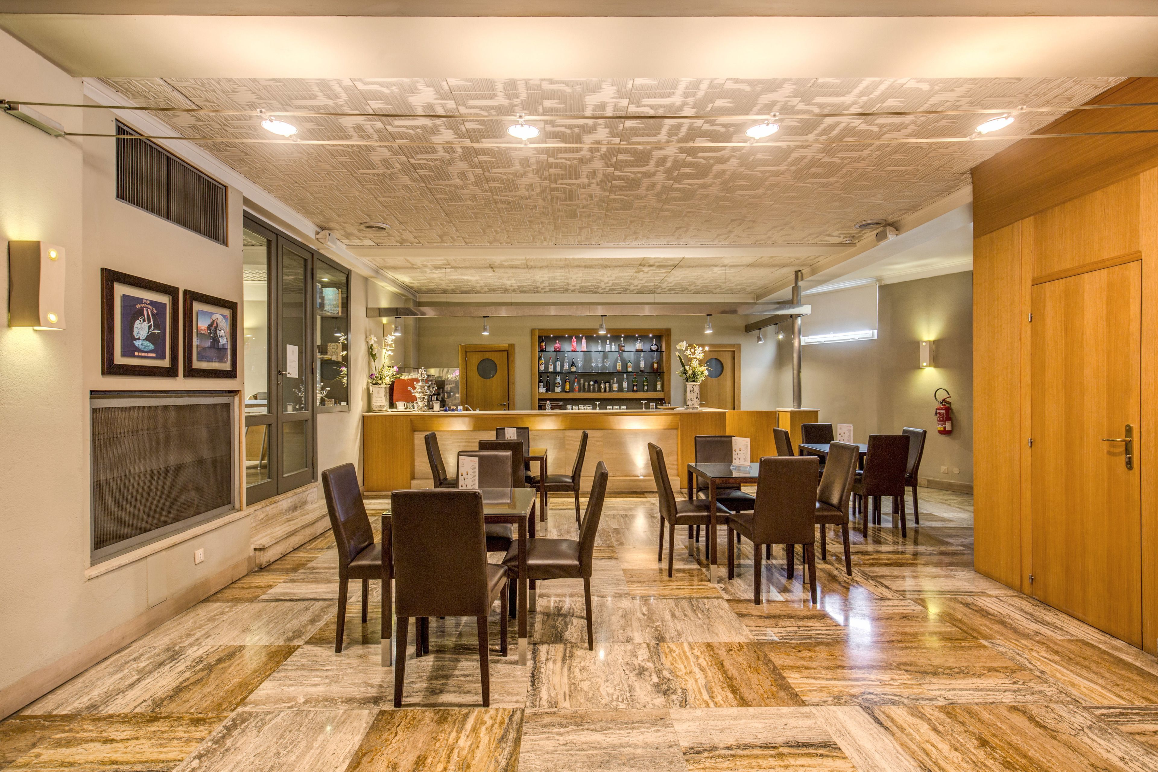 Um hall de hotel com área de bar, disposi ção de assentos e um extintor de incêndio na parede.