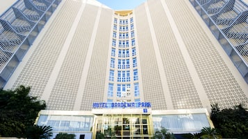 Um hotel alto com fachada marcante, apresentando um padrão em forma de grade e uma entrada central.