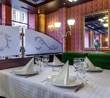 Um restaurante com uma mesa posta para quatro pessoas, incluindo pratos, copos e talheres.