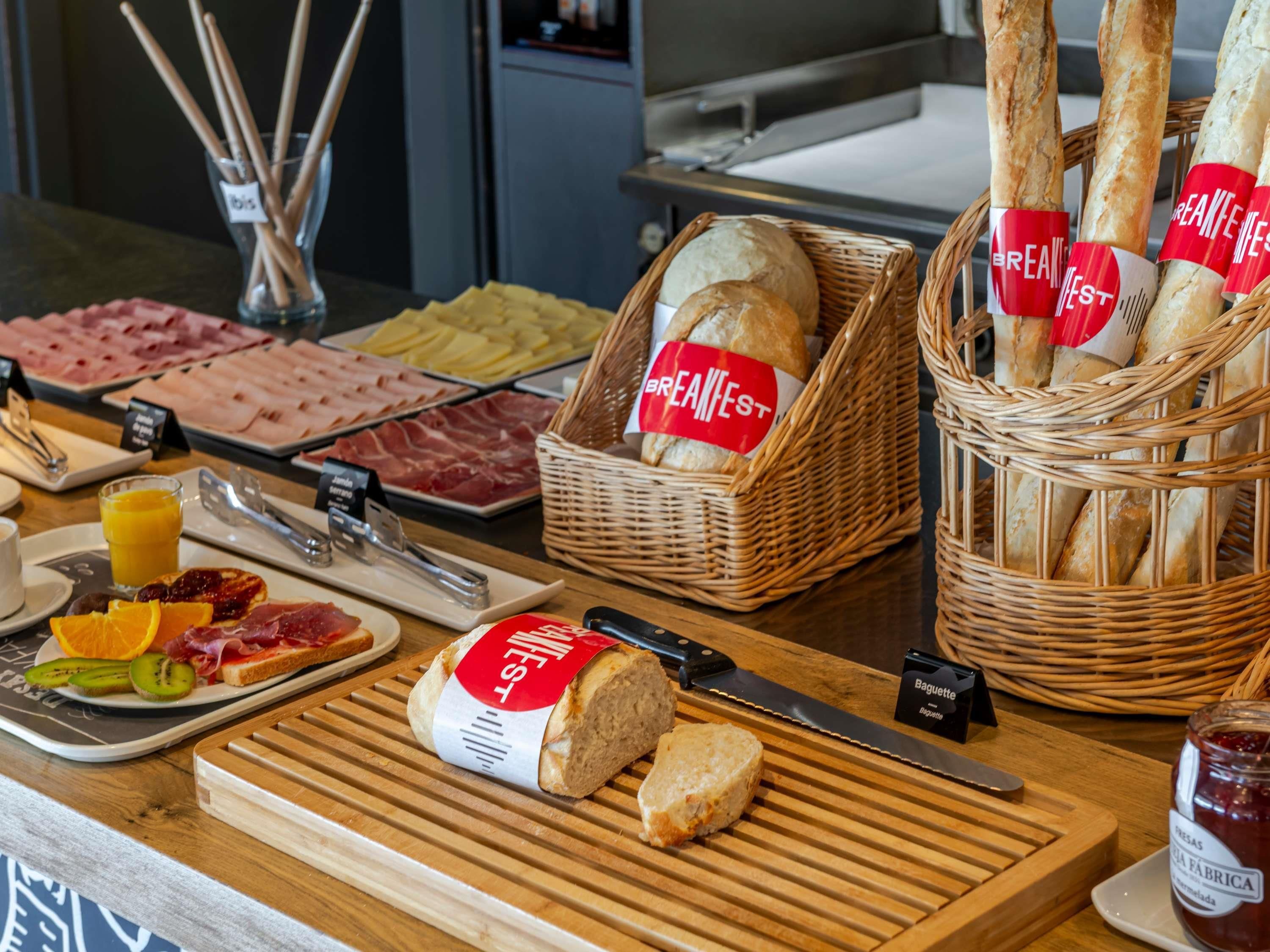Buffet de café da manhã com diversos tipos de carne, pães e frutas.