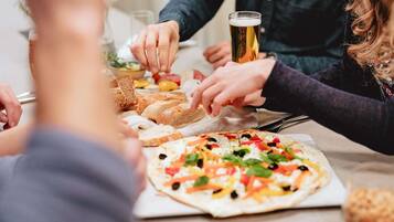 Um grupo de pessoas jantando juntas, com pizza e um copo de cerveja na mesa.