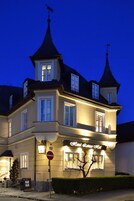 Um hotel com arquitetura europeia clássica, com vários beirais e uma placa bem visível.