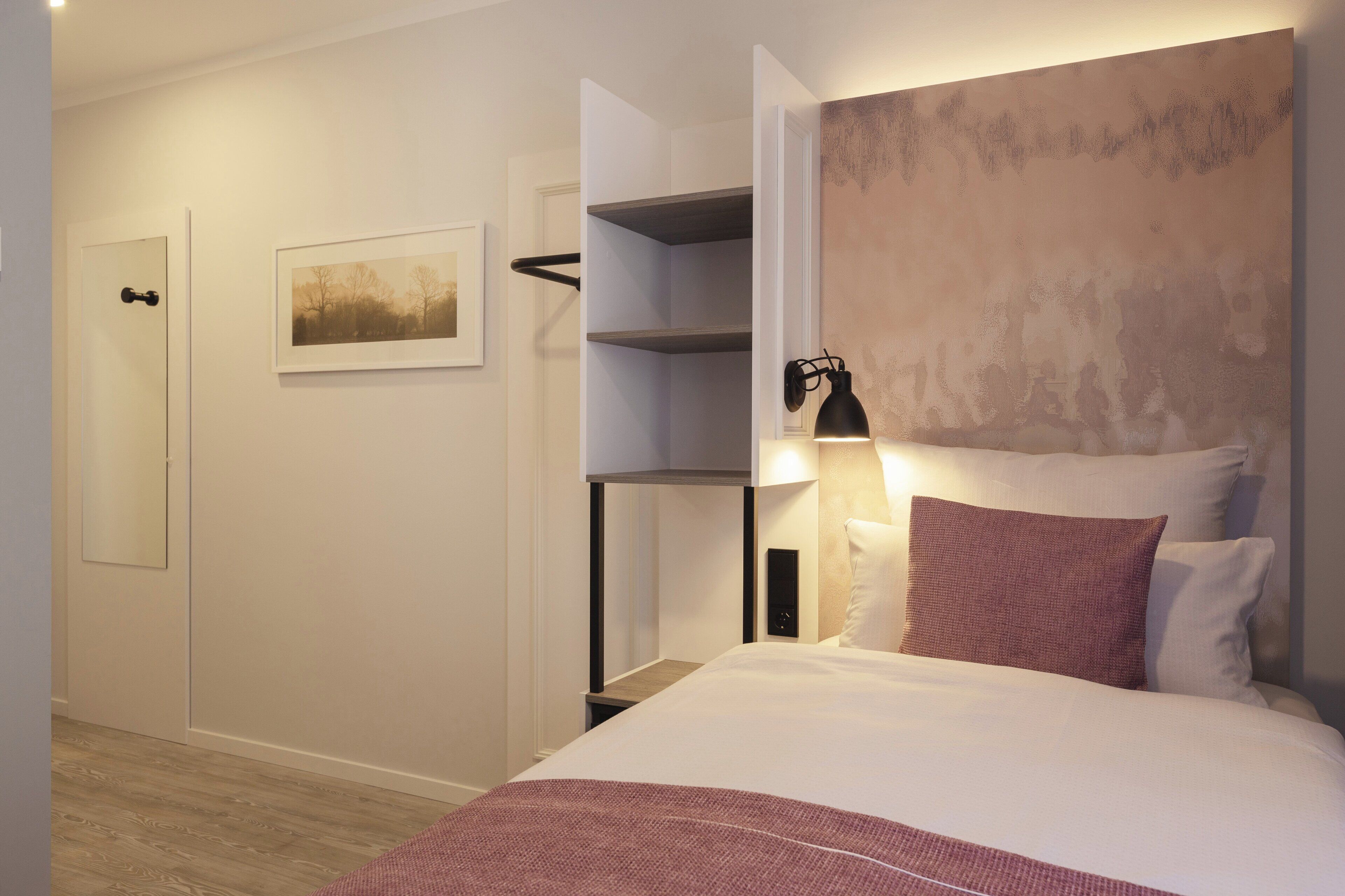 Um quarto moderno com uma cama, uma mesa de cabeceira, uma luminária e um aparador.