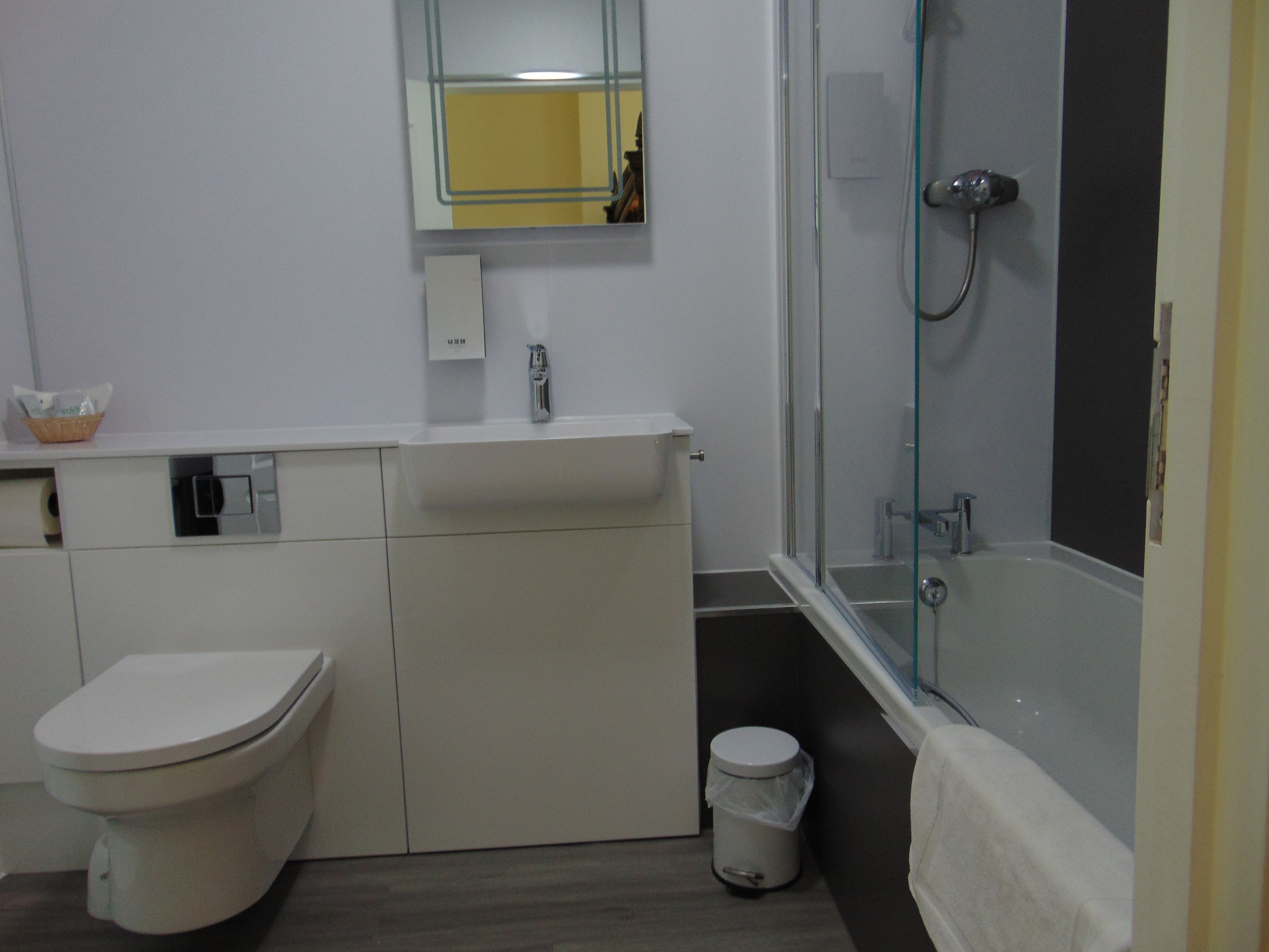 Uma casa de banho moderna com sanita, lavatório e chuveiro.