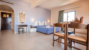 Quarto de hotel com cama, escrivaninha, cadeira, espelho e janela com cortinas.