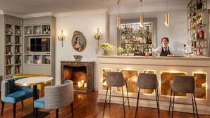 Uma área de bar com um bartender, uma lareira e um balcão com banquetas.