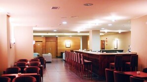 Um saguão de hotel com balcão de recepção, área de estar e um longo balcão com cadeiras.