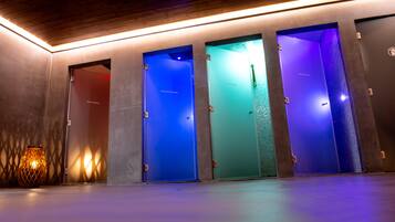 Um corredor com quatro portas, cada uma iluminada com cores diferentes.