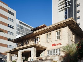 Um hotel com fachada clássica, entrada destacada com toldo e a inscrição 'ibis HOTEL'.