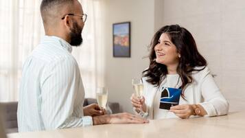 Um homem e uma mulher sentados à mesa com taças de champanhe, segurando um cartão.