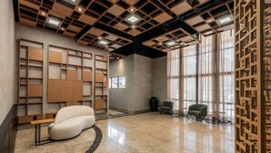 Um hall amplo com design moderno, com uma grande área de estar, uma parede de estantes de madeira e janelas amplas que permitem a entrada de luz natural.