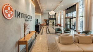 Um lobby moderno com balcão de atendimento, área de estar e amplas janelas.