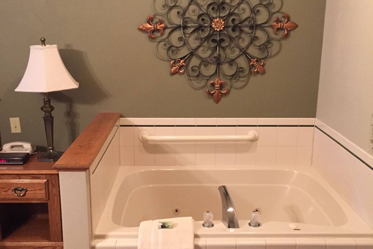 Casa de banho com banheira, um ornamento na parede, uma lâmpada e toucador com espelho.