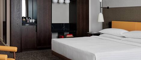 Quarto de hotel com uma cama grande, um guarda-roupa de madeira, uma mesinha e um espelho.