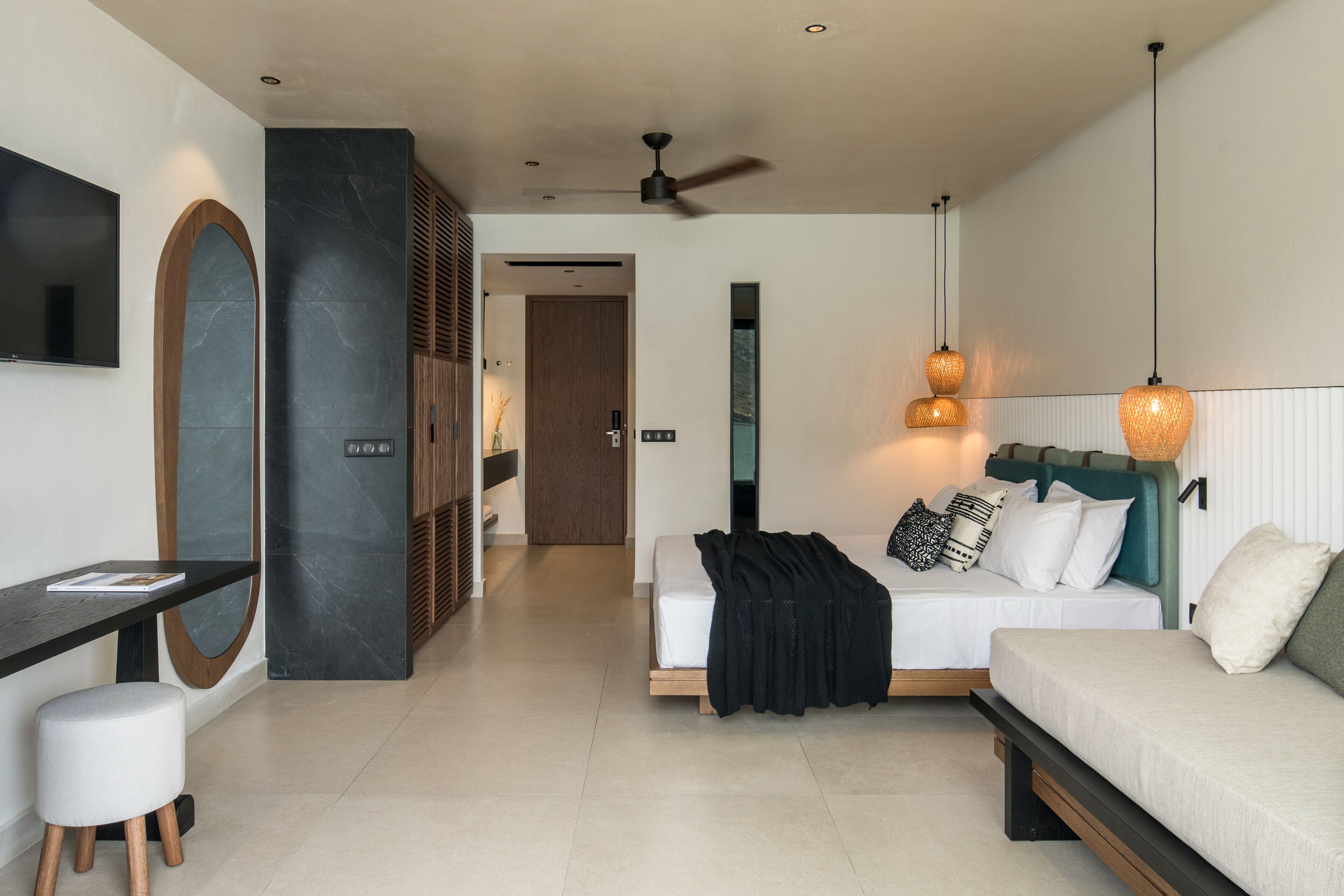 Quarto de hotel moderno com cama, escrivaninha, cadeira e televisão.