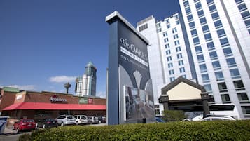 Placa de hotel com vista para o horizonte urbano, um estacionamento e um edifício com toldo vermelho.