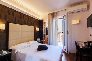 Quarto de hotel com uma cama grande, uma escrivaninha com cadeira, televisão e porta de vidro que se abre para o exterior.