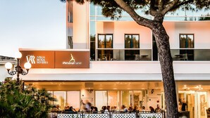 Um hotel moderno com uma placa visível para 'Villa Rosa Riviera' e serviços de 'Personal Trainer'.